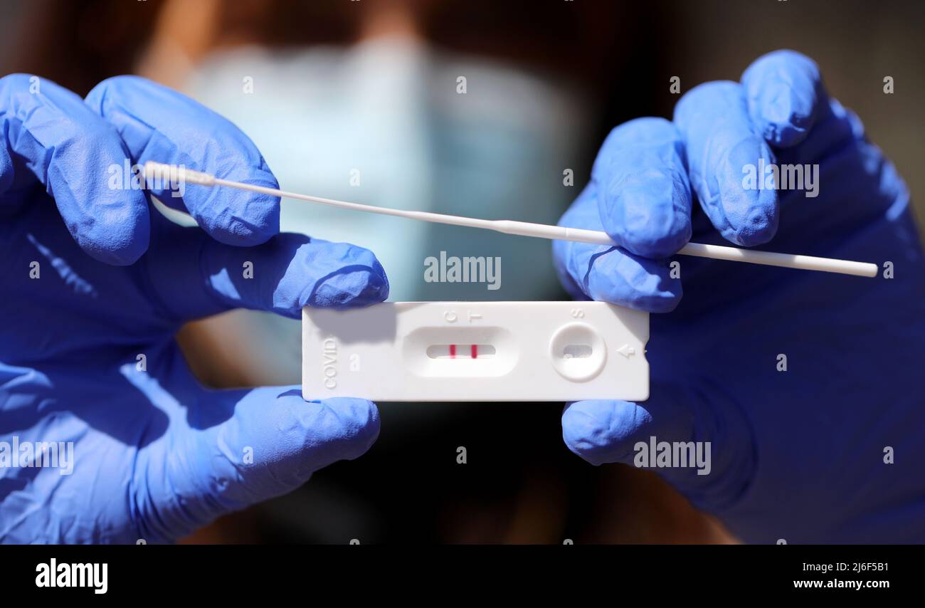 blue gloved hands of female doctor holding test stick with two lines ...