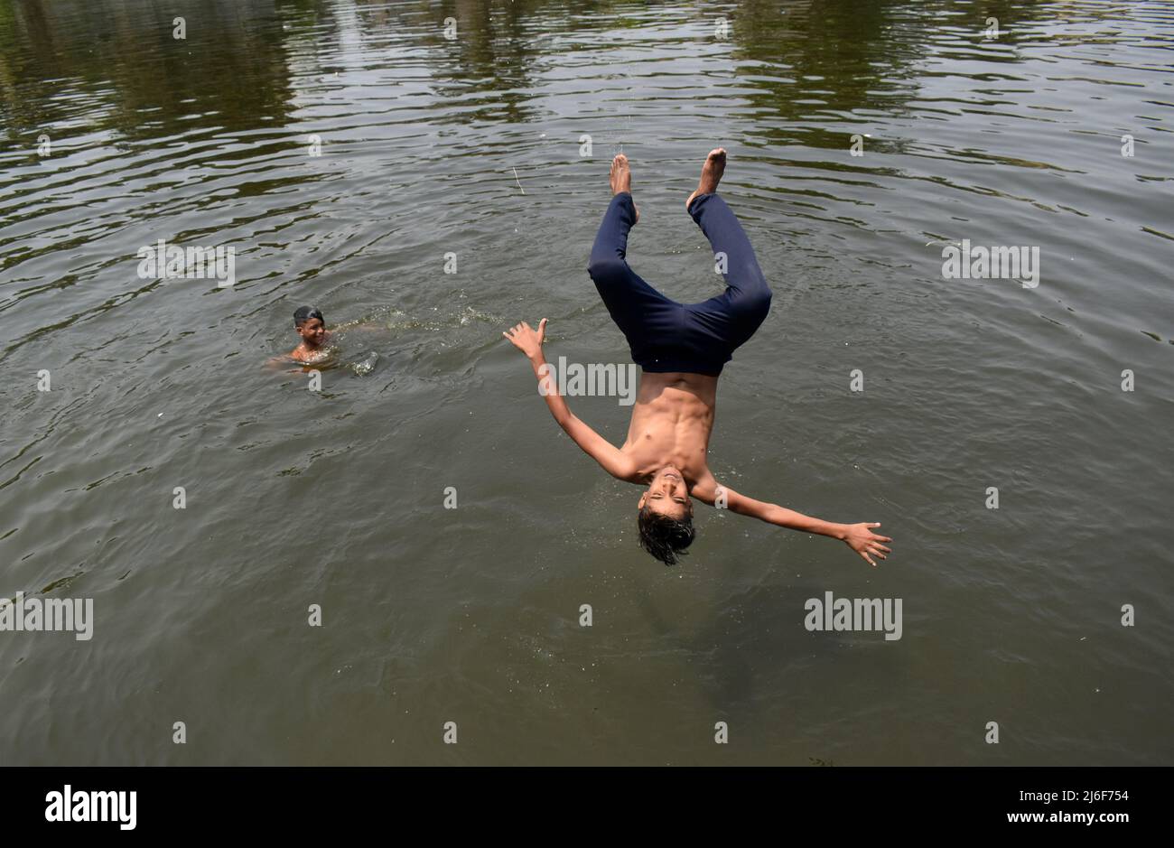 A boy jumps into a pond to cool off on a hot summer day on the ...