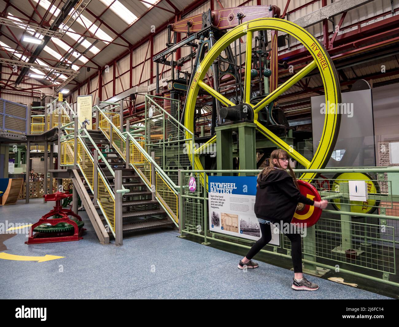 A young girl tries to set in motion the principle of the fly-wheel to ...