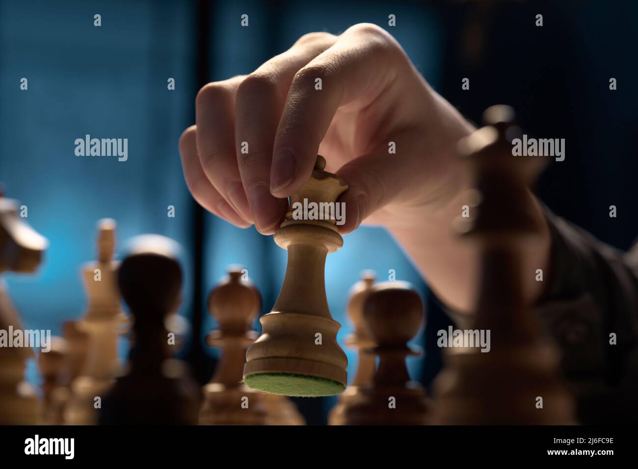 Man playing chess and moving a piece on the chessboard, hand close up ...