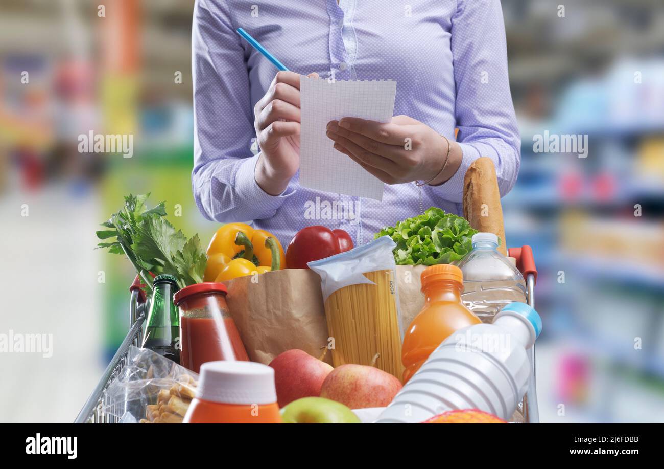 Woman checking a shopping list and buying goods at the supermarket, her ...