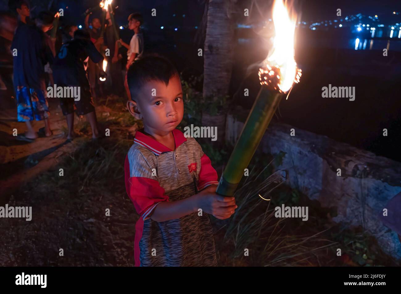 A child is seen holding a torch during the torch parade to welcome Eid ...