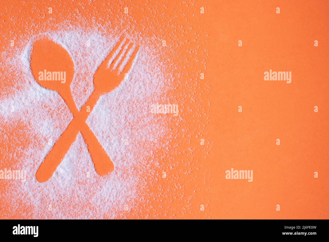 Crossed spoon and fork figure created in sugar relief on orange ...