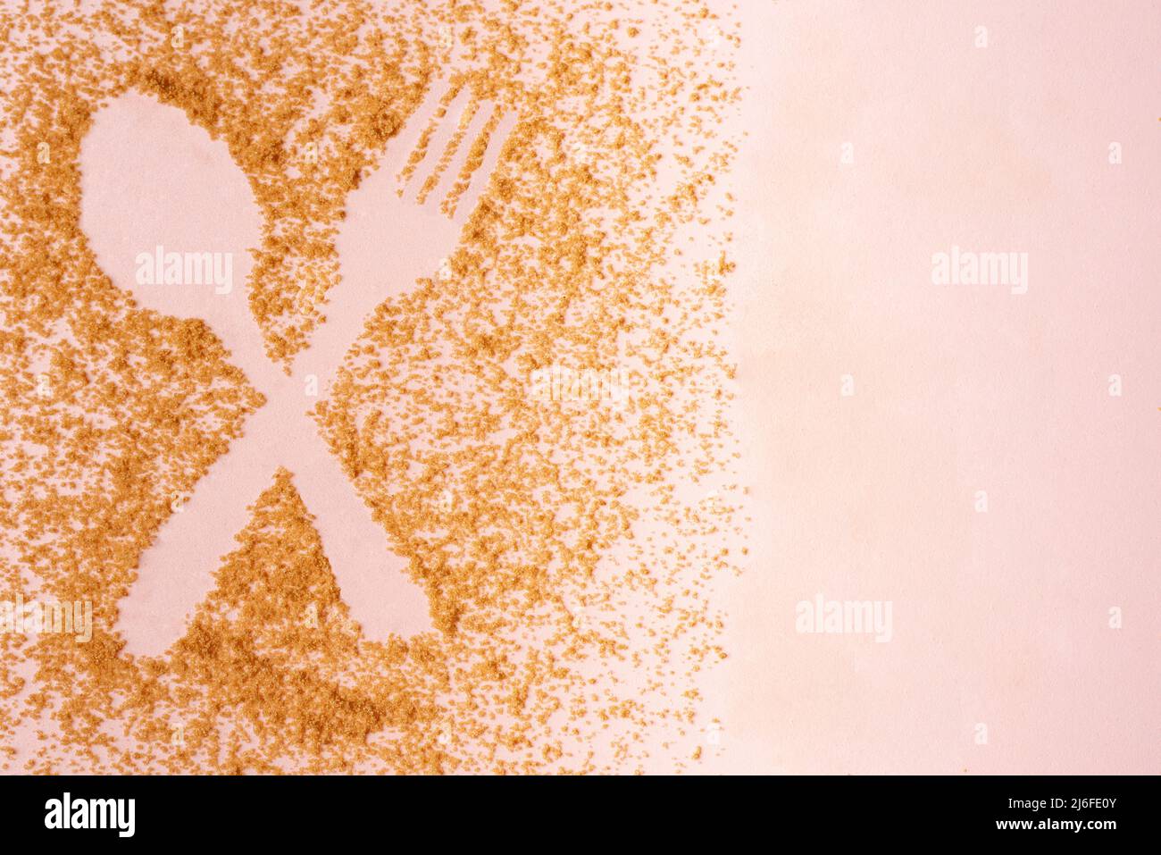 Crossed spoon and fork figure created in relief of muscovado sugar on ...