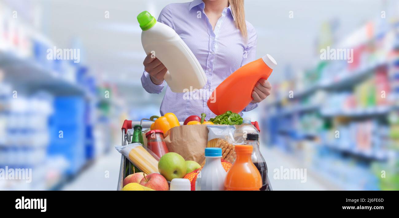 Woman doing grocery shopping at the supermarket and comparing products ...