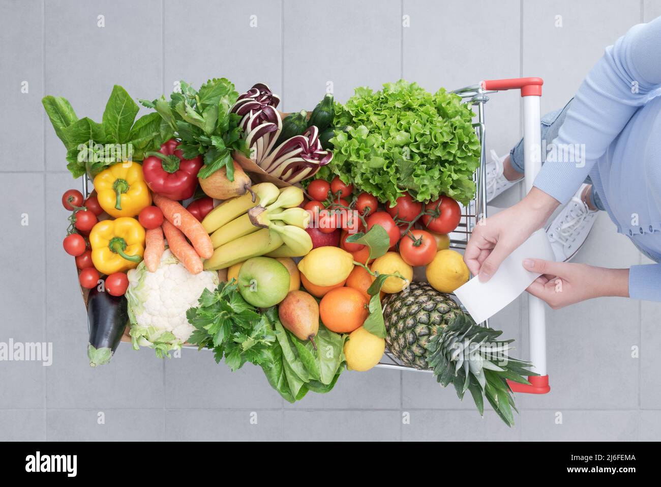 Woman buying a lot of fresh vegetables and fruits, she is checking the ...