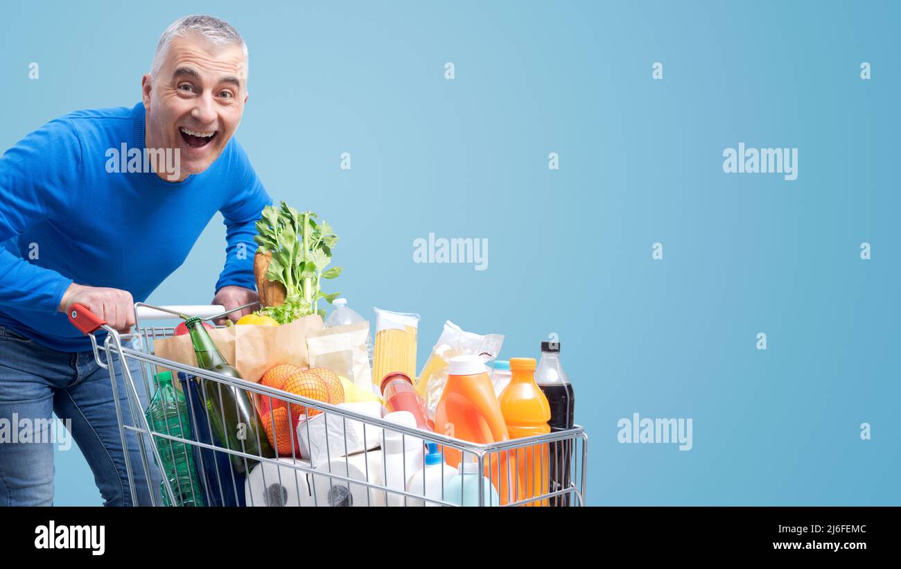 Smiling excited man pushing a shopping cart full of groceries Stock ...