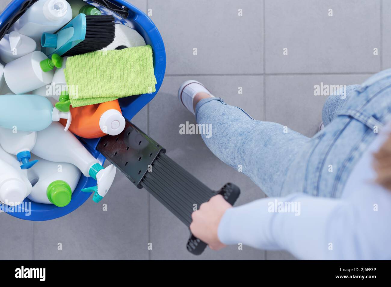 Woman pulling a shopping basket full of cleaning products at the store ...