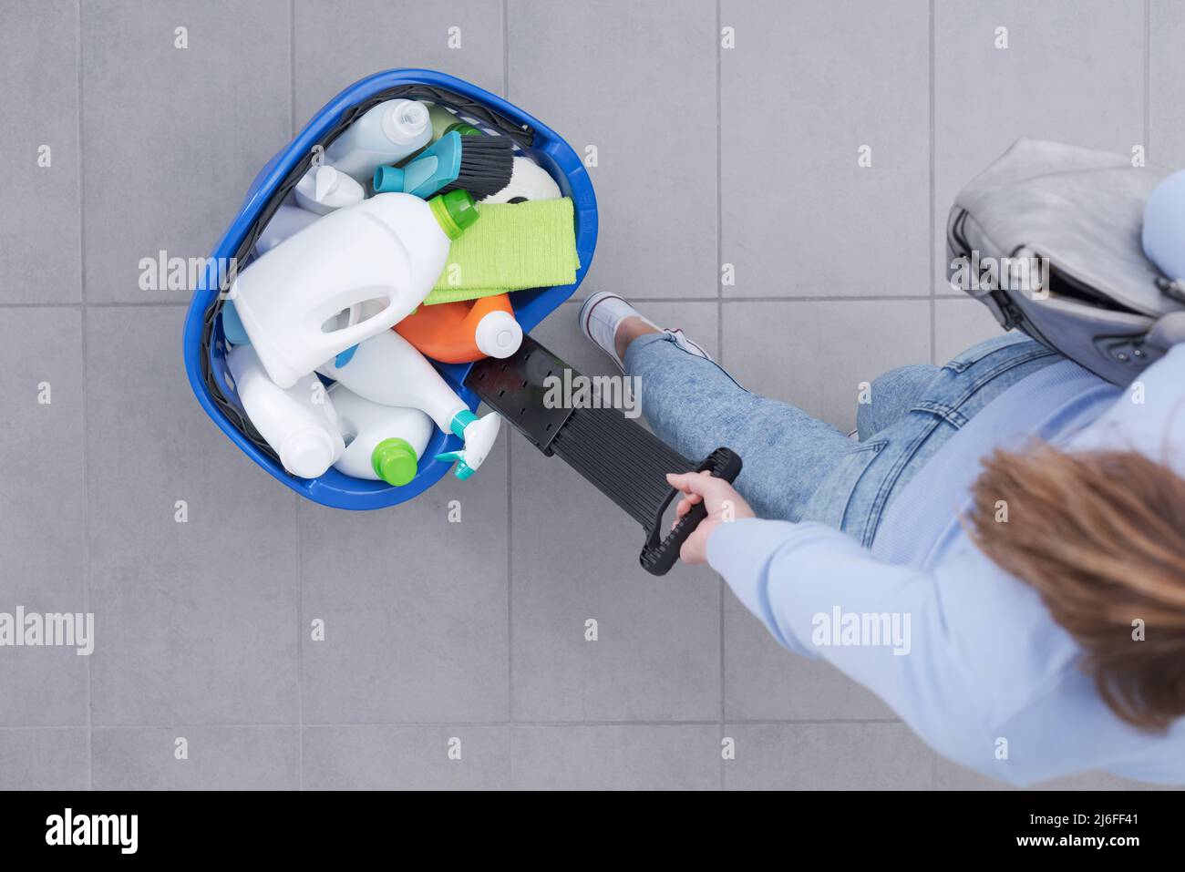 Woman pulling a shopping basket full of cleaning products at the store ...
