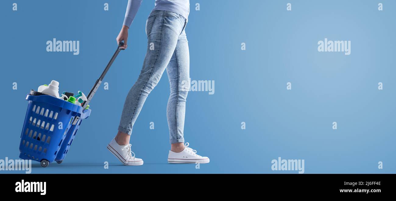 Woman pulling a shopping basket full of cleaning products, blank copy ...