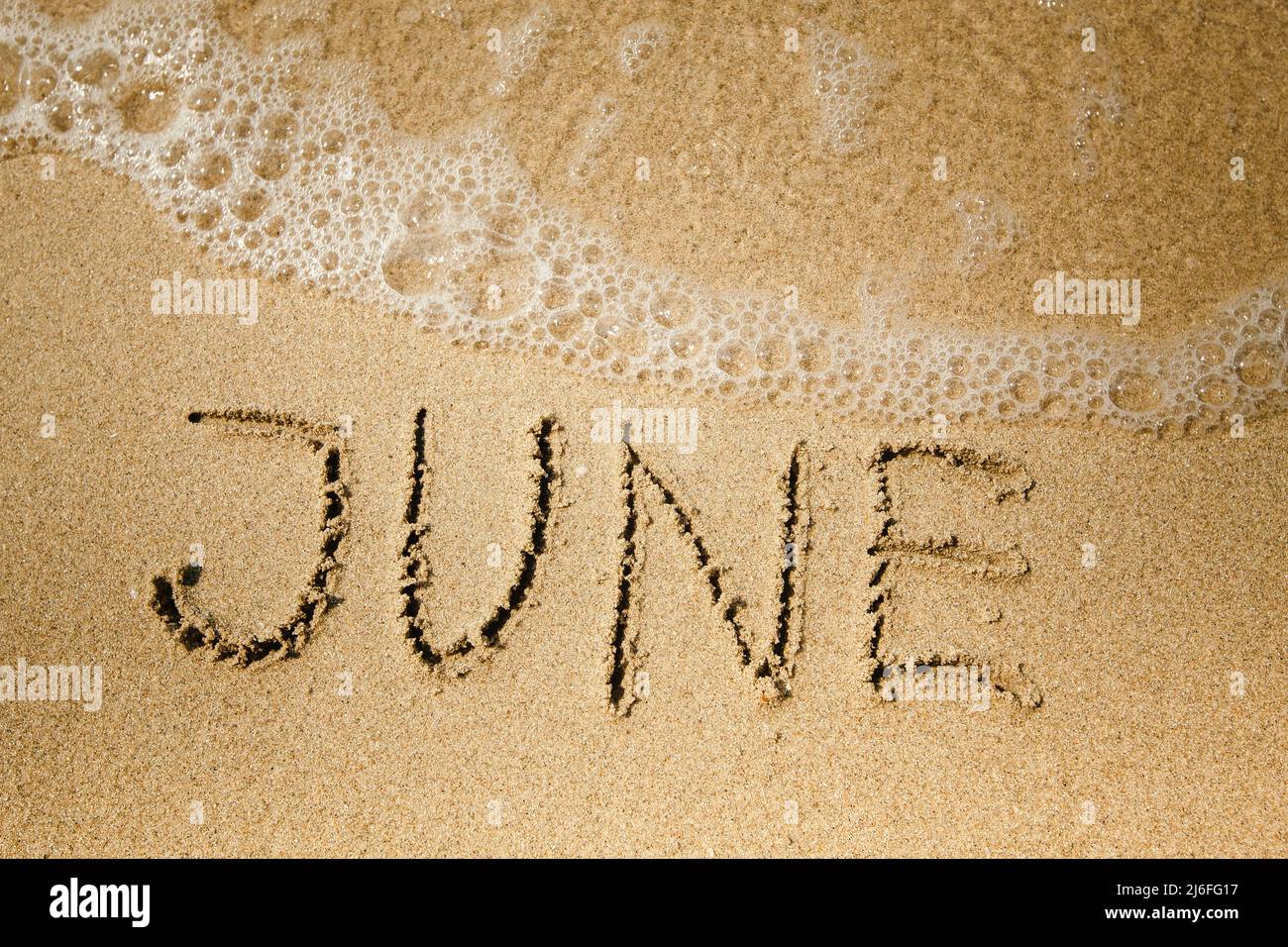 June - handwritten on the soft beach sand Stock Photo - Alamy