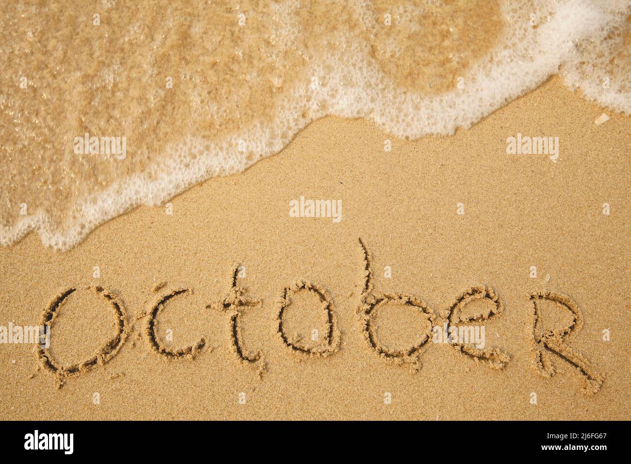 October - handwritten on the soft beach sand Stock Photo - Alamy