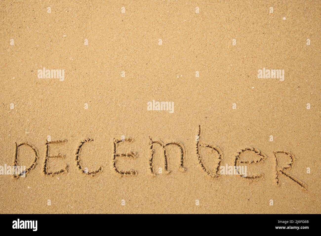 December - handwritten on the soft beach sand Stock Photo - Alamy