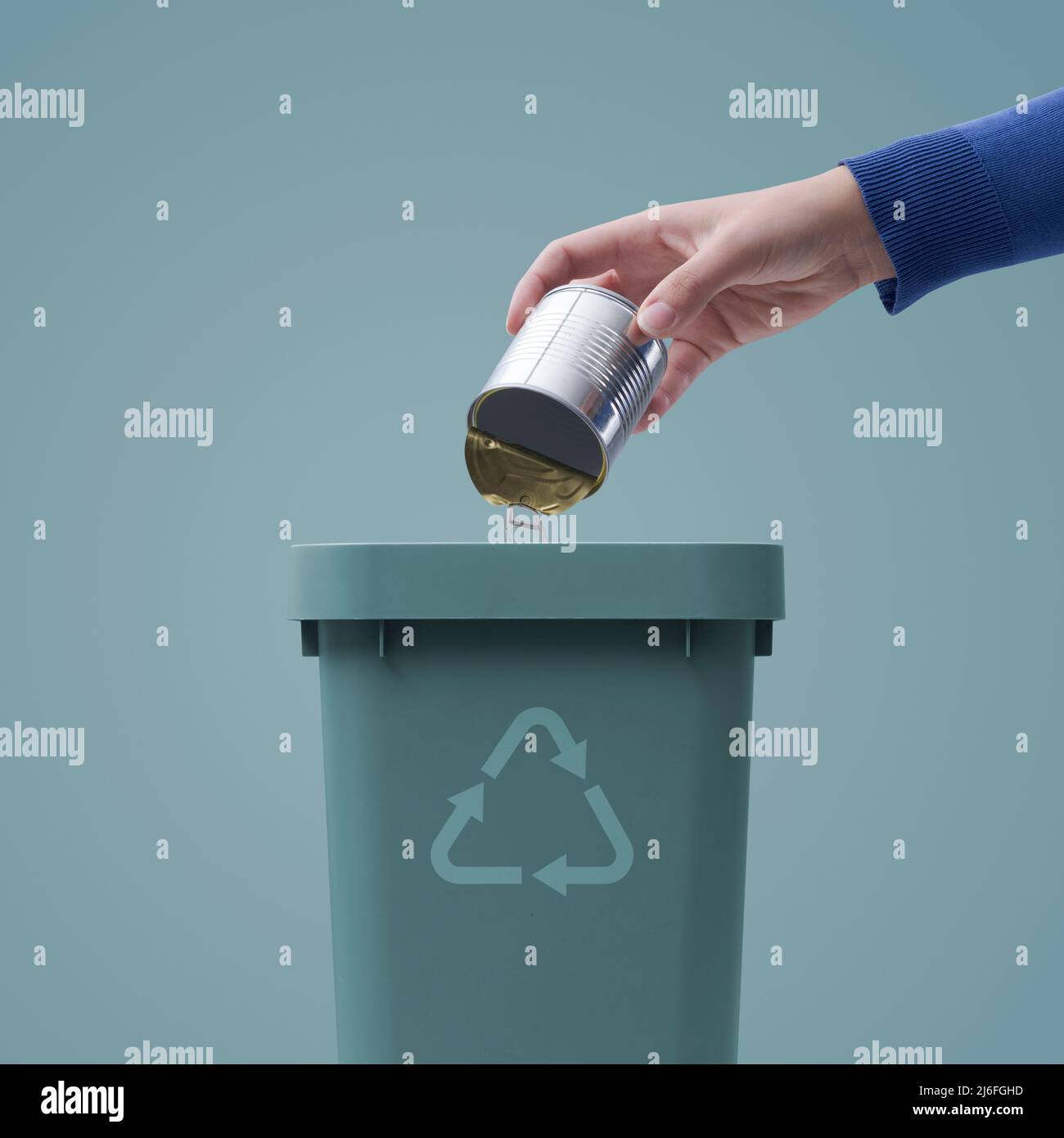 Woman putting a tin in the trash bin, waste sorting and recycling ...