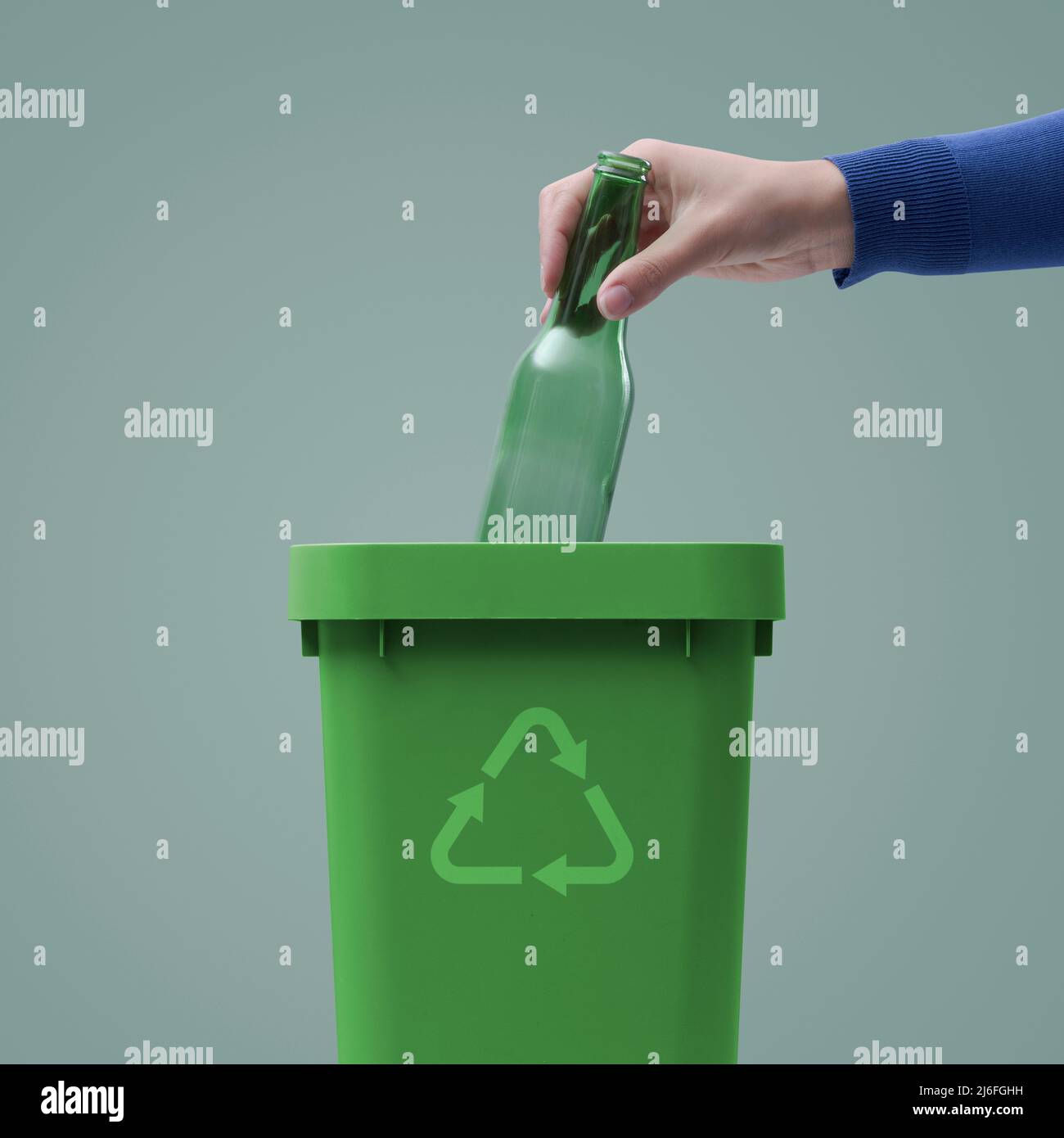 Woman putting an empty glass bottle in the trash bin, separate waste ...