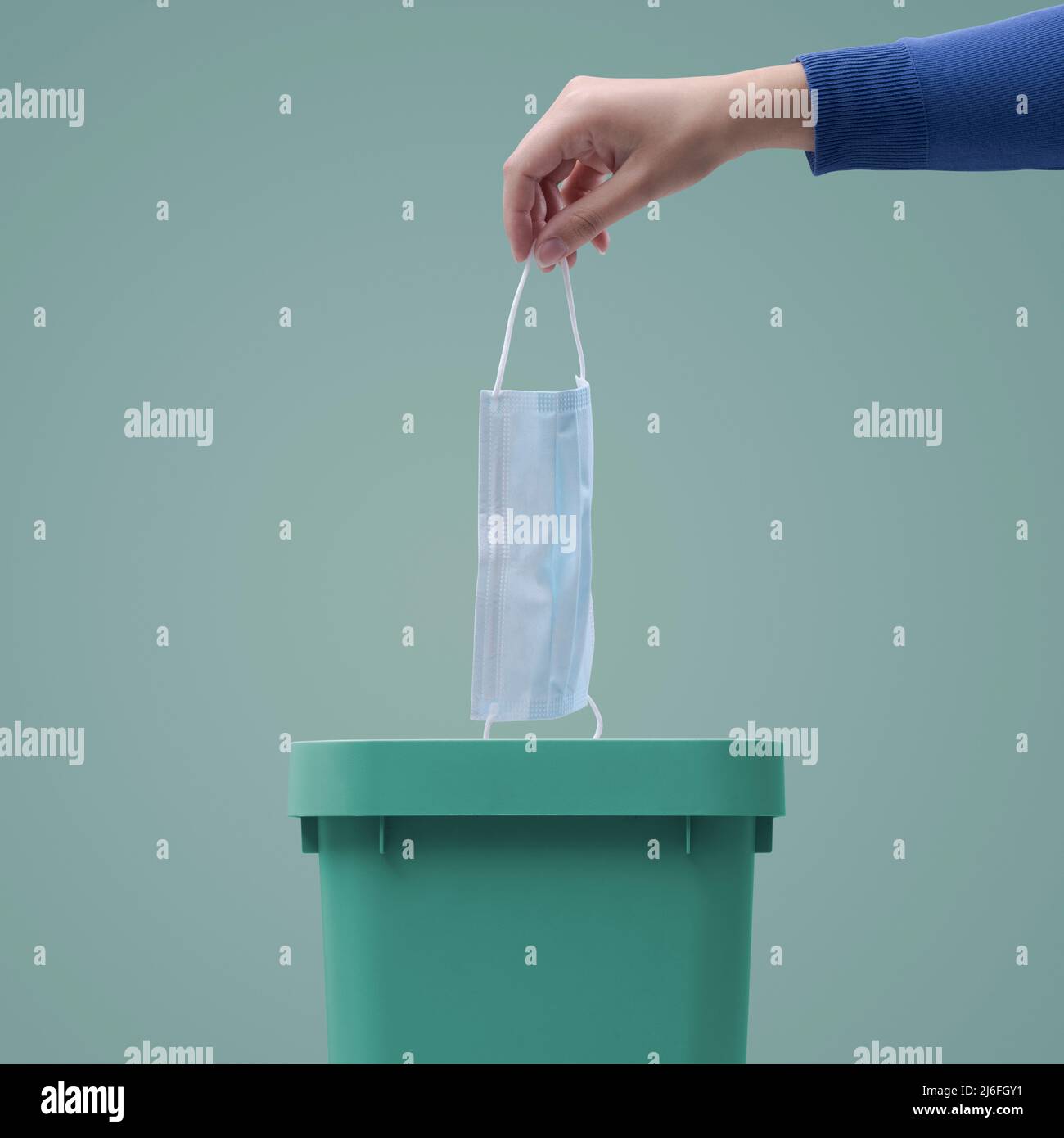 Woman putting an used face mask in the trash bin, medical waste ...