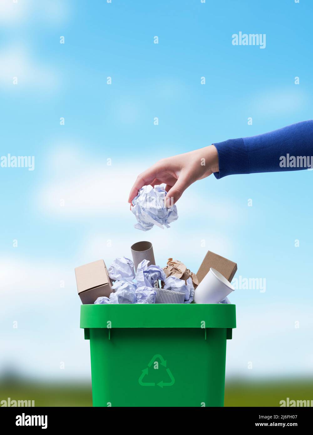 Woman putting paper in the waste bin, separate waste collection and ...