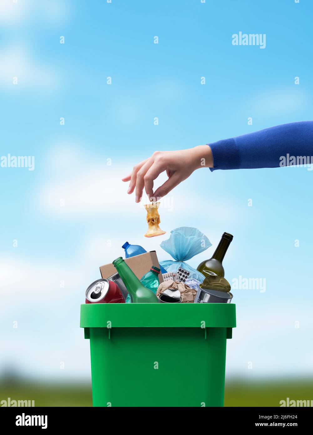 Woman putting food leftovers in a undifferentiated waste bin, improper ...