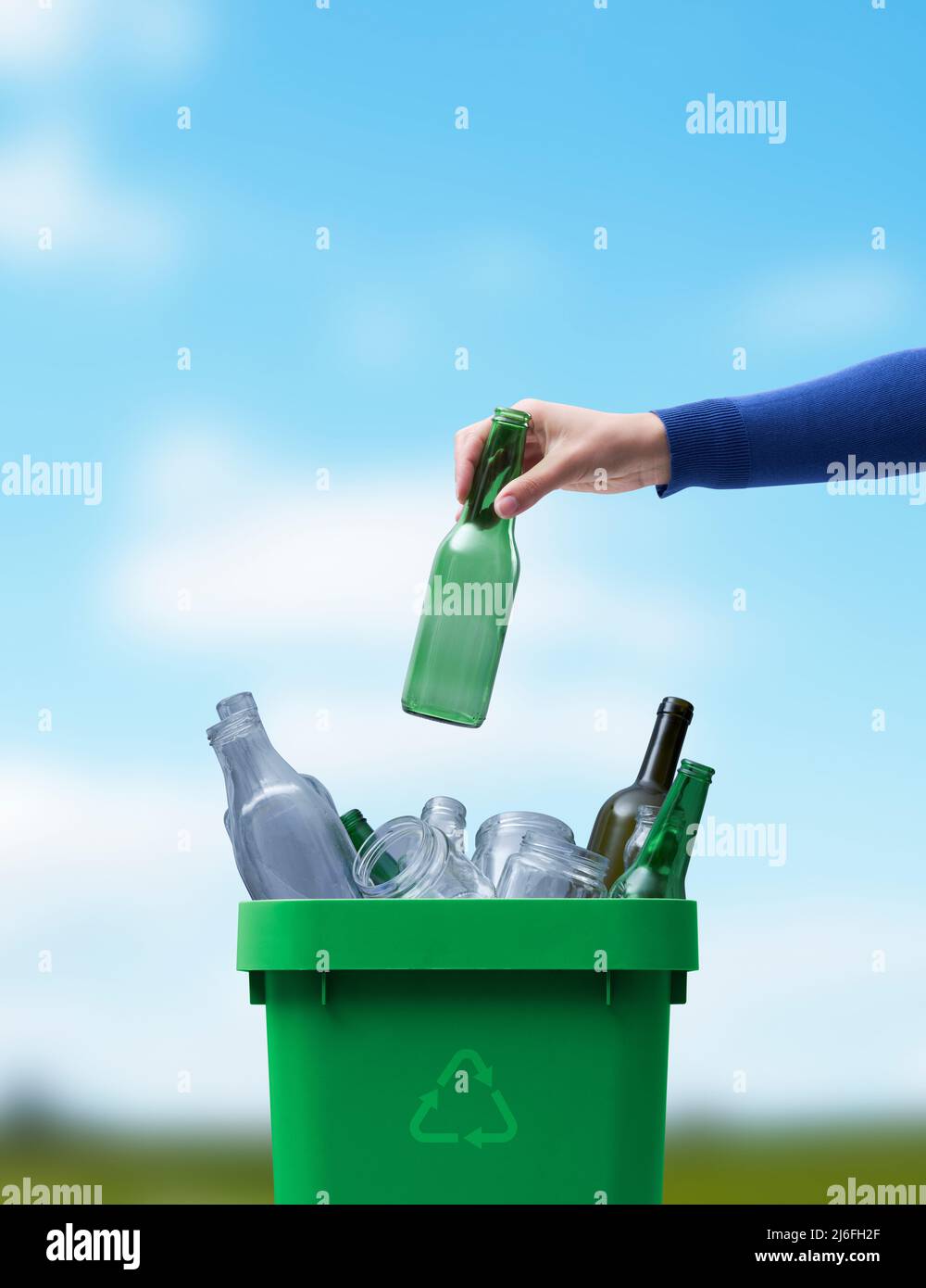 Woman putting a glass bottle in the trash bin, separate waste ...