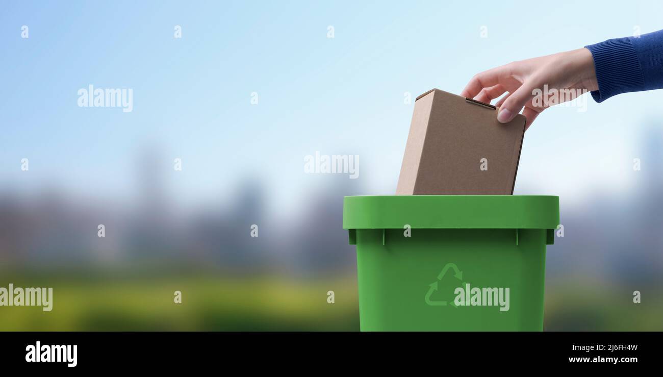 Woman putting a cardboard box package in the trash bin, separate waste ...
