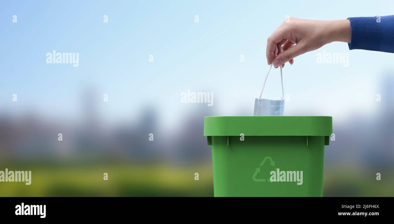 Woman putting an used face mask in the trash bin, medical waste ...