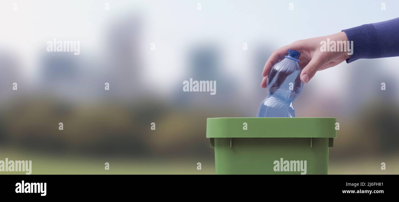 Woman putting a plastic bottle in a trash bin, waste sorting and ...