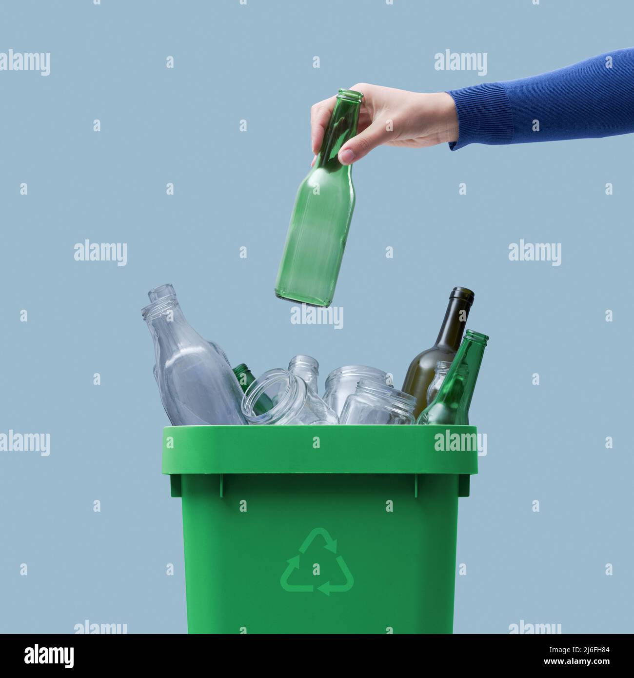 Woman putting a glass bottle in the trash bin, separate waste ...