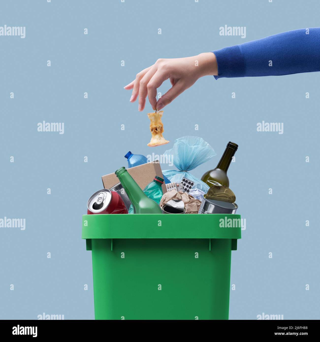 Woman putting food leftovers in undifferentiated waste bin, improper ...