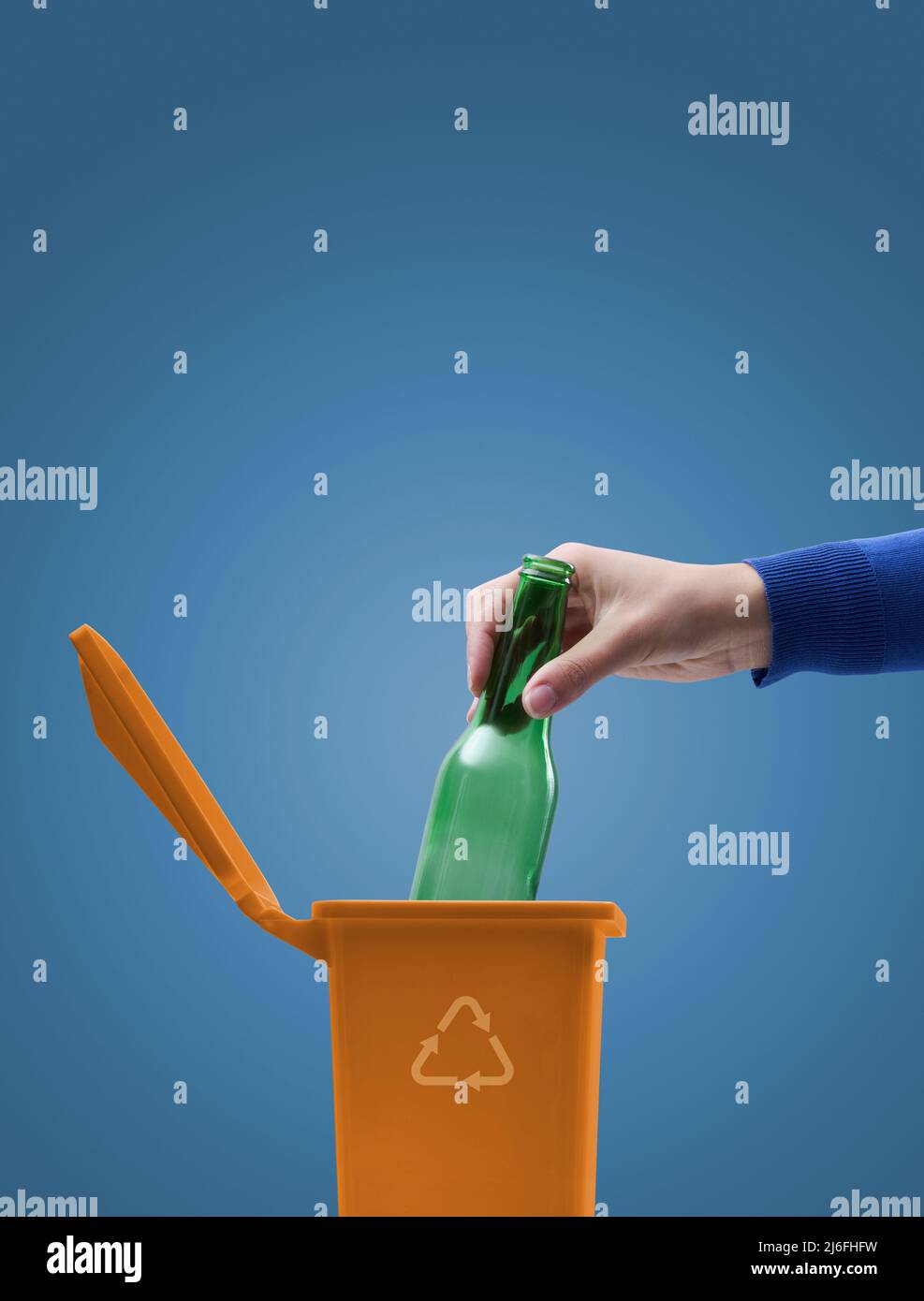 Woman putting an empty glass bottle in the trash bin, separate waste ...