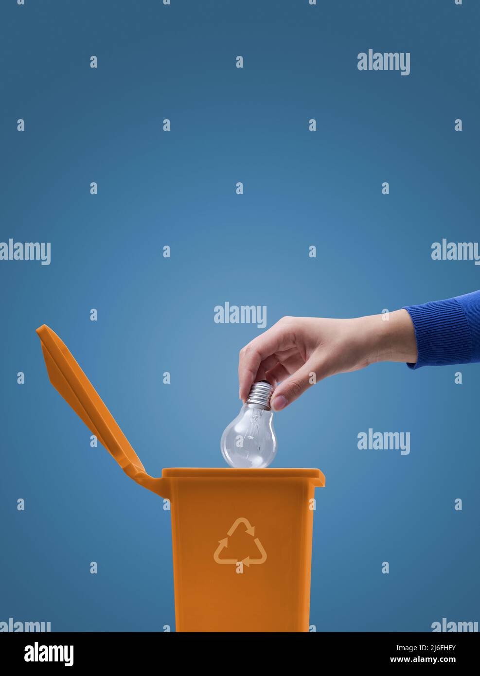 Woman putting an incandescent lightbulb in the waste bin, recycling and ...