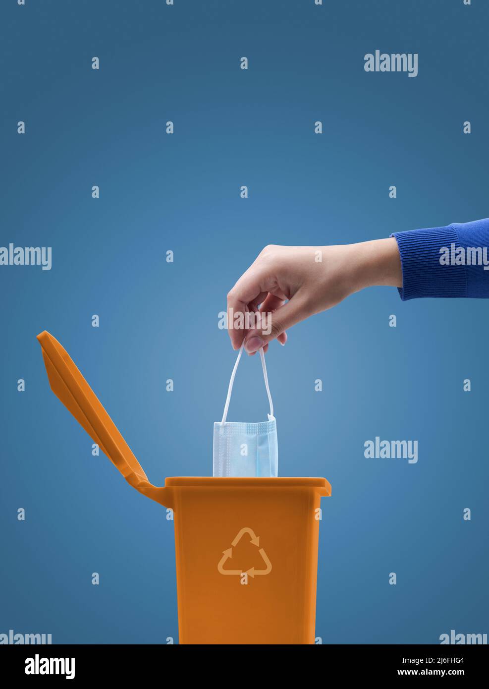 Woman putting an used face mask in the trash bin, medical waste ...