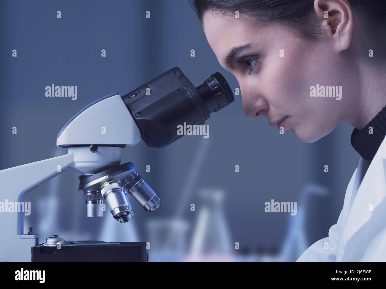 Young researcher working in the lab, she is looking through a ...