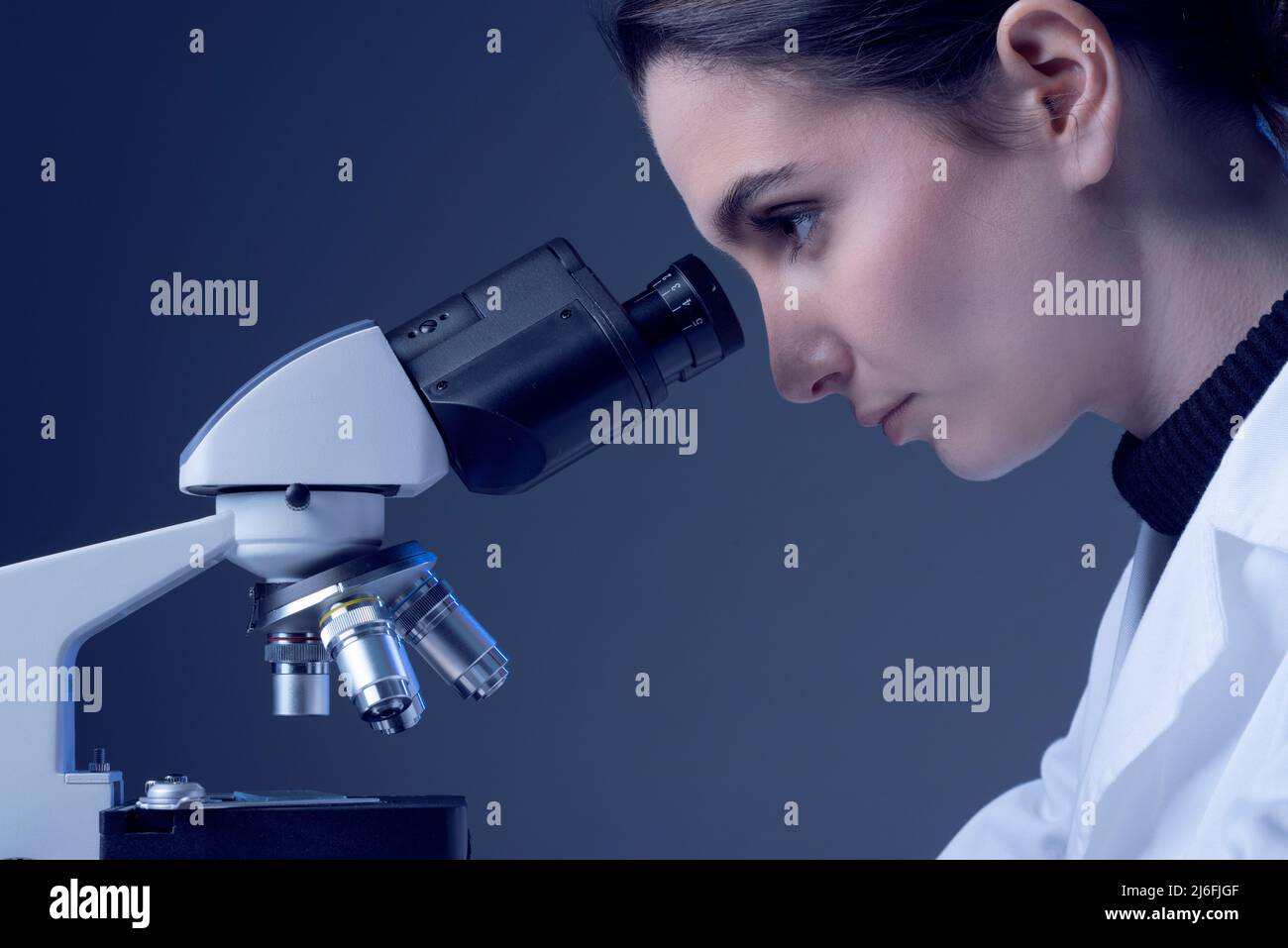 Young researcher looking through a microscope and checking samples ...