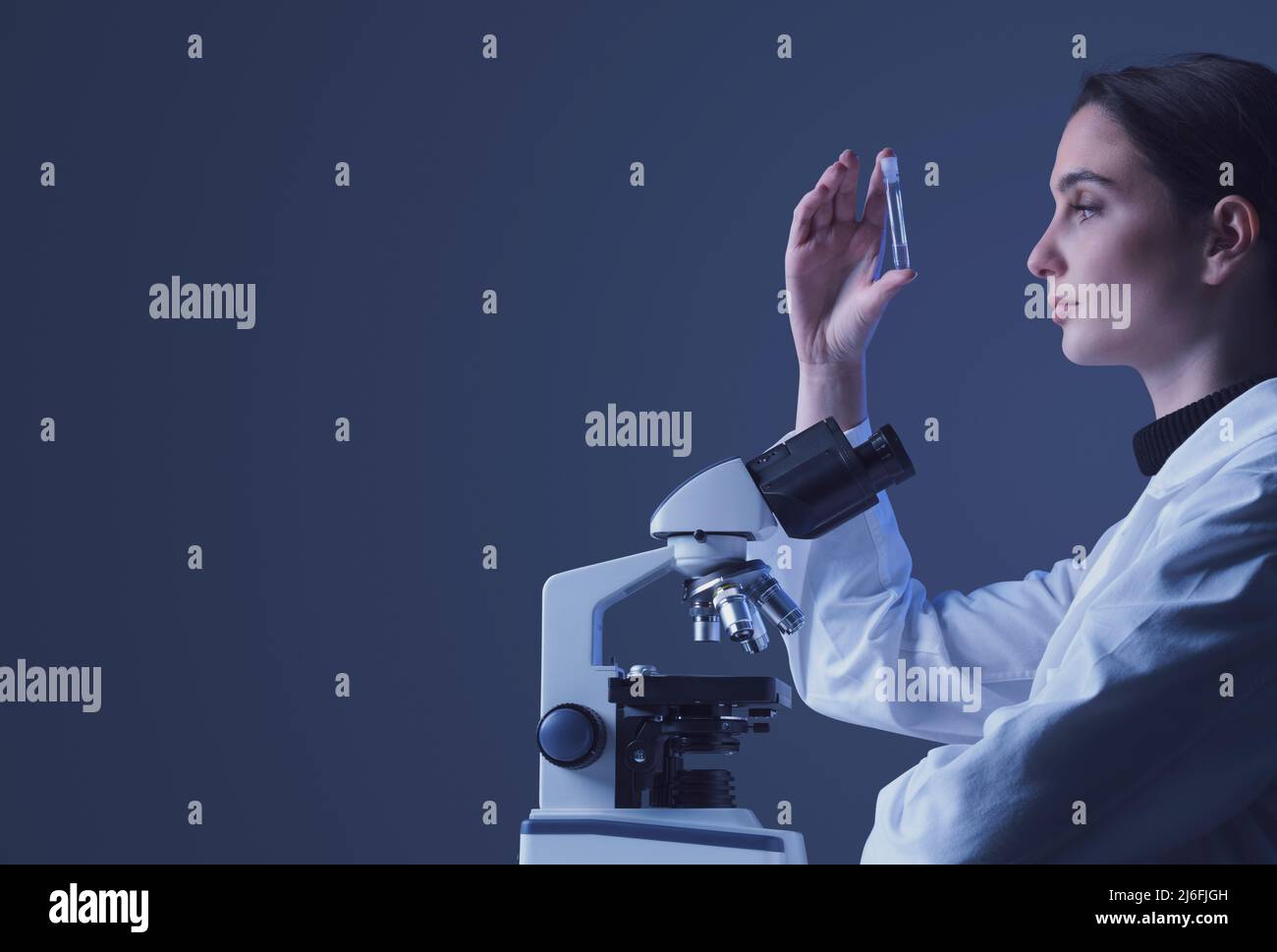 Young scientist holding a test tube and using a microscope, medicine ...