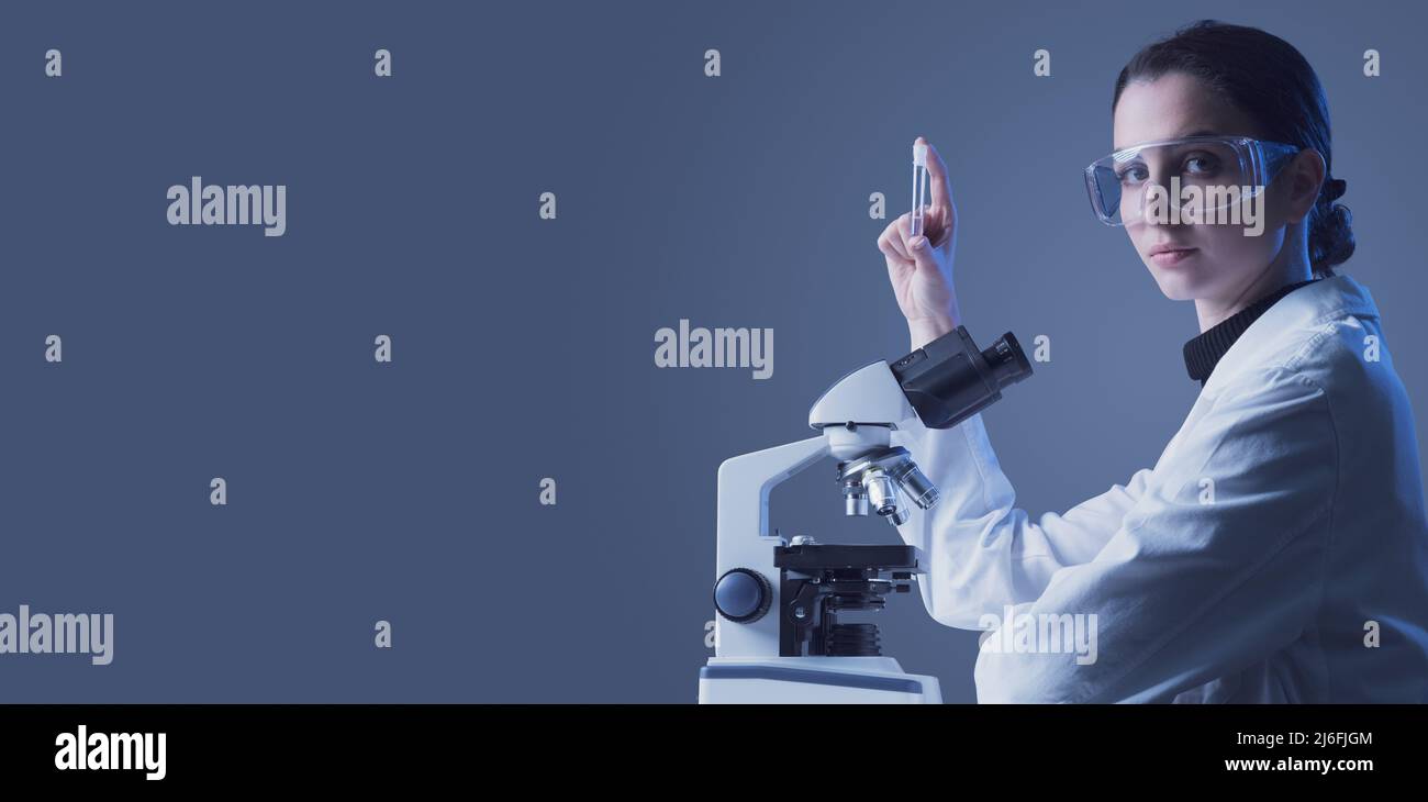 Young scientist holding a test tube and using a microscope, medicine ...