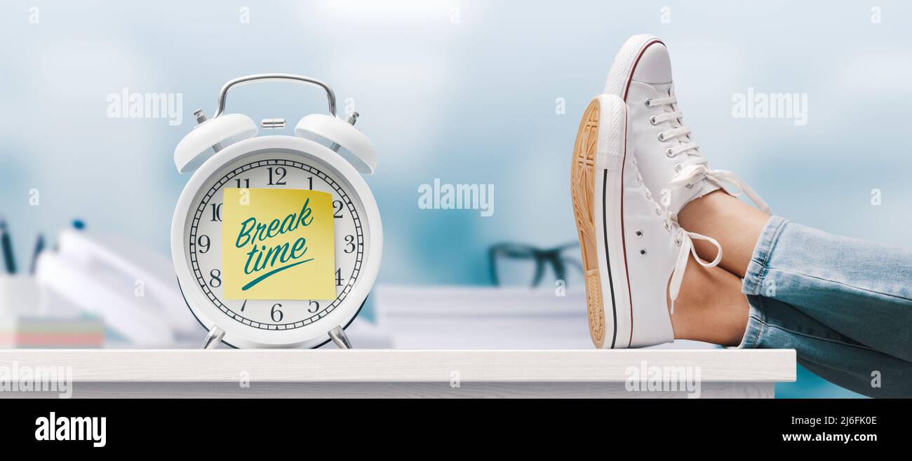 Woman relaxing with feet up in the office and alarm clock with sticky ...