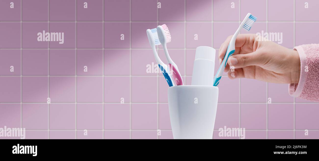 Woman taking her toothbrush in the bathroom, she is cleaning her teeth ...