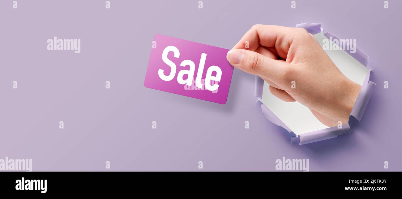 Customer hand breaking through a torn paper hole and holding a ...
