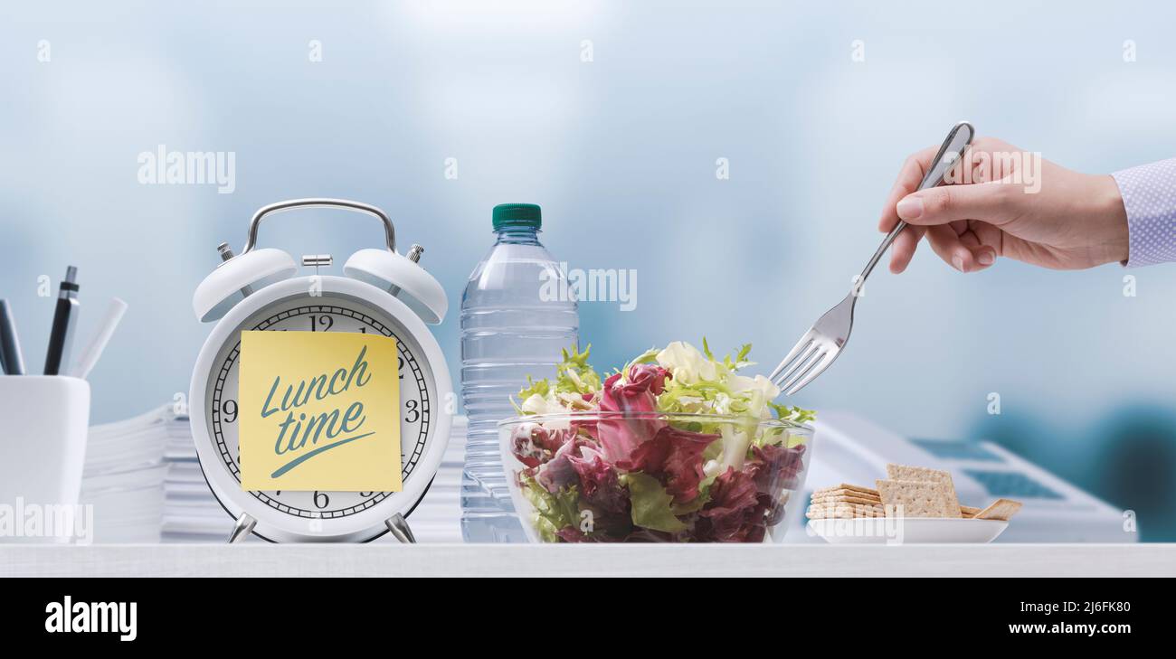 Woman eating a fresh healthy salad during her lunch break at work Stock ...