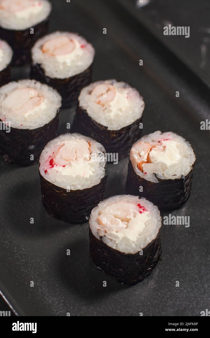 Simple maki with shrimp on a plate on black stone background. Flat lay ...