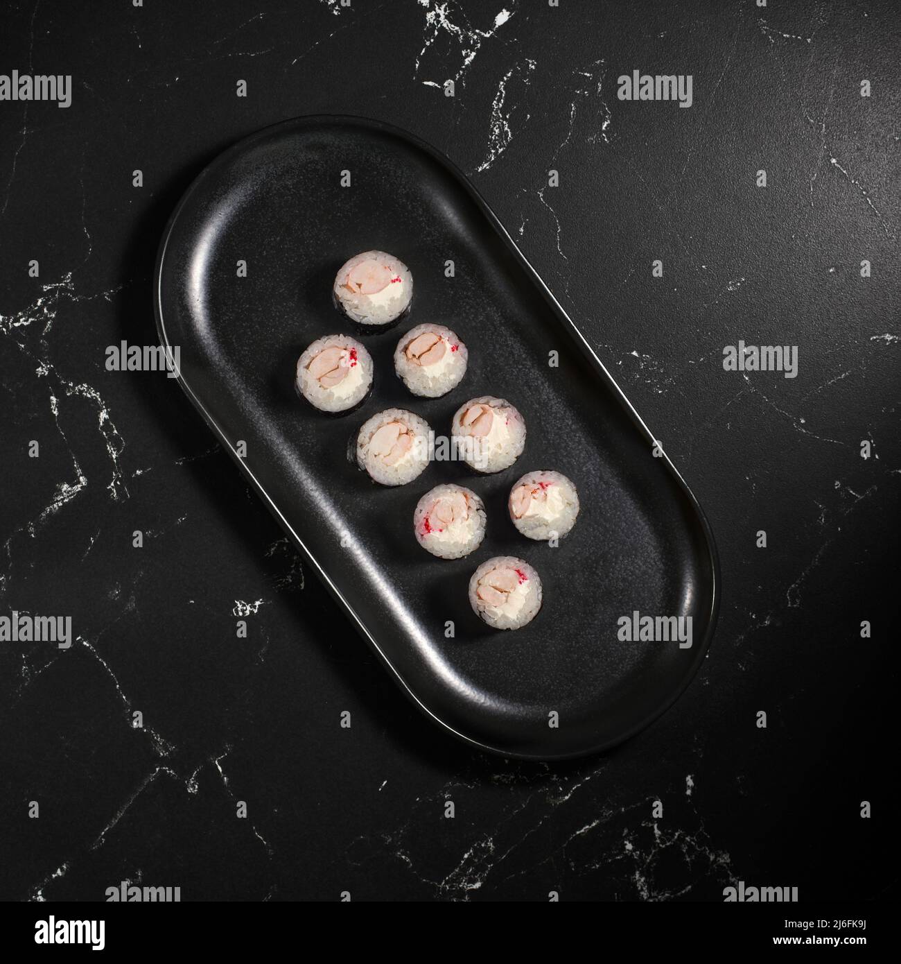 Simple maki with shrimp on a plate on black stone background. Flat lay ...