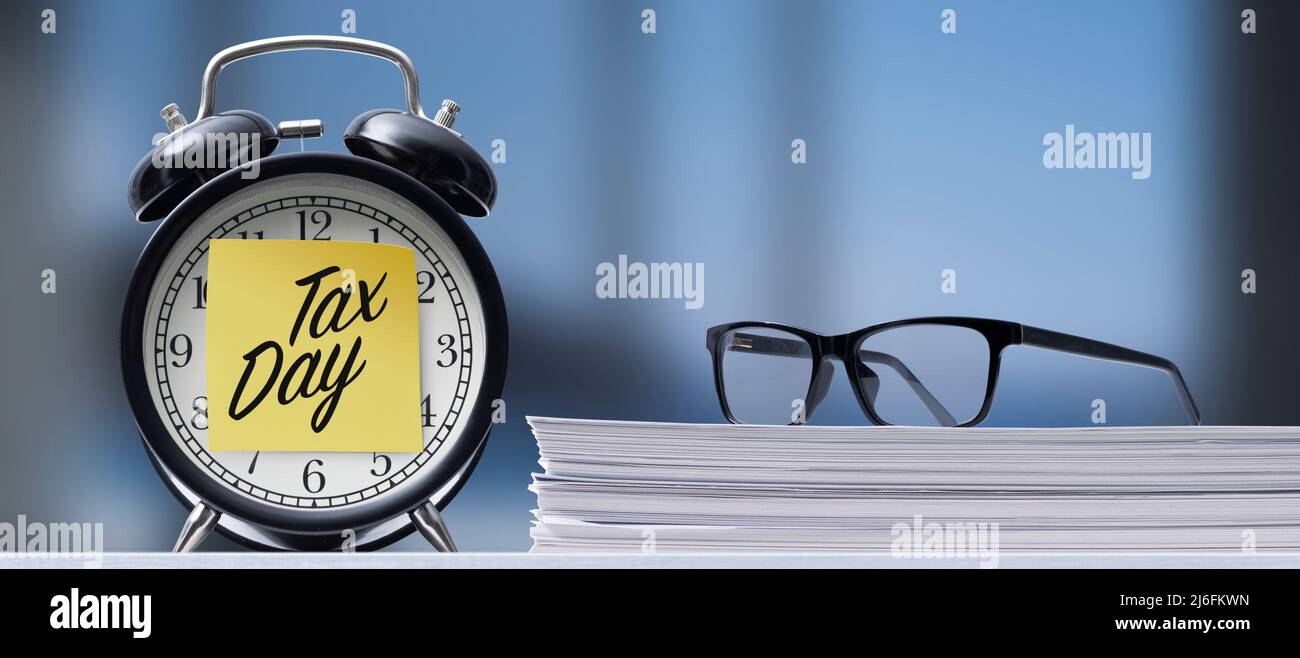 Tax day reminder on a clock and pile of paperwork Stock Photo - Alamy