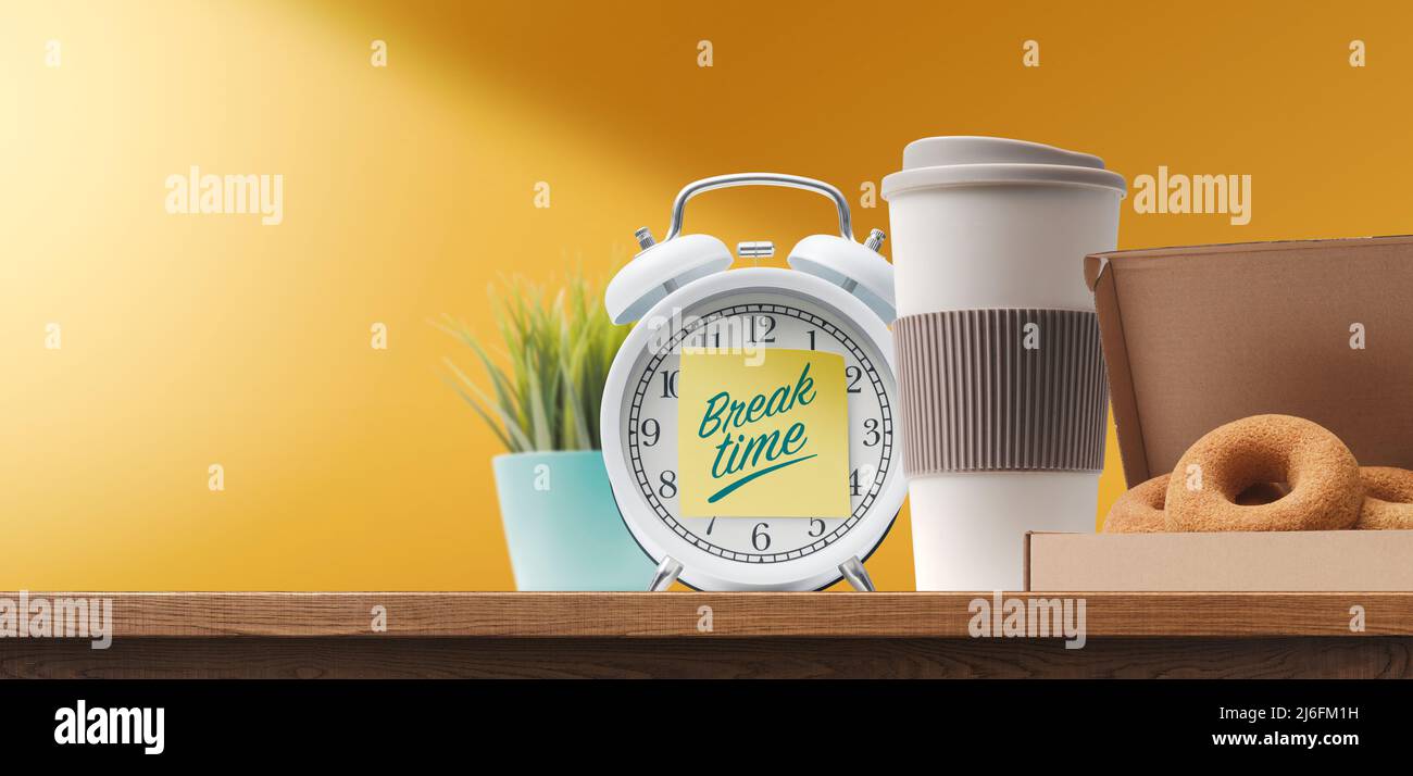 Coffee, donuts and alarm clock on the office desk: it's break time ...