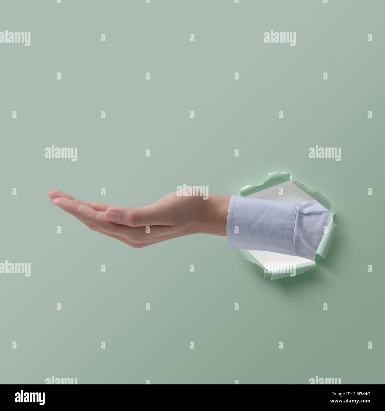 Outstretched female hand through torn paper, help and assistance ...