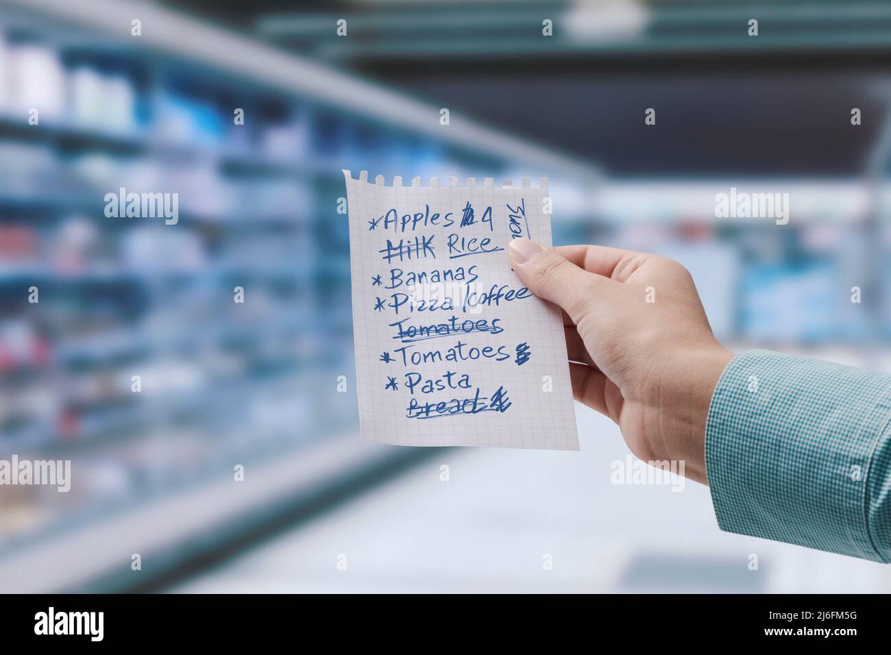 Woman holding a messy handwritten shopping list and supermarket aisle ...