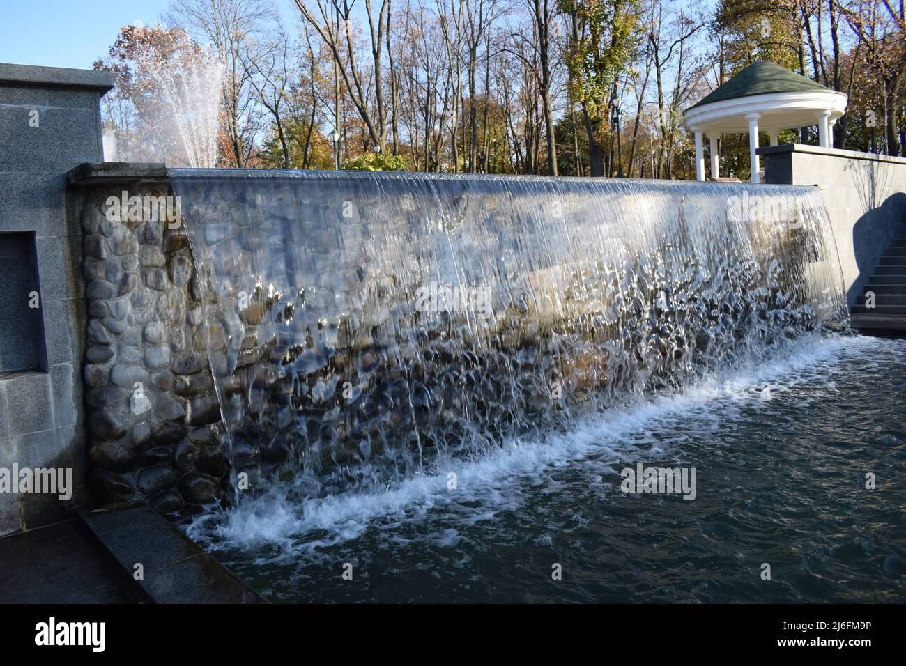 A waterfall flowing at park. A waterfall of a fountain in a garden. Wall of water. A beautiful ...