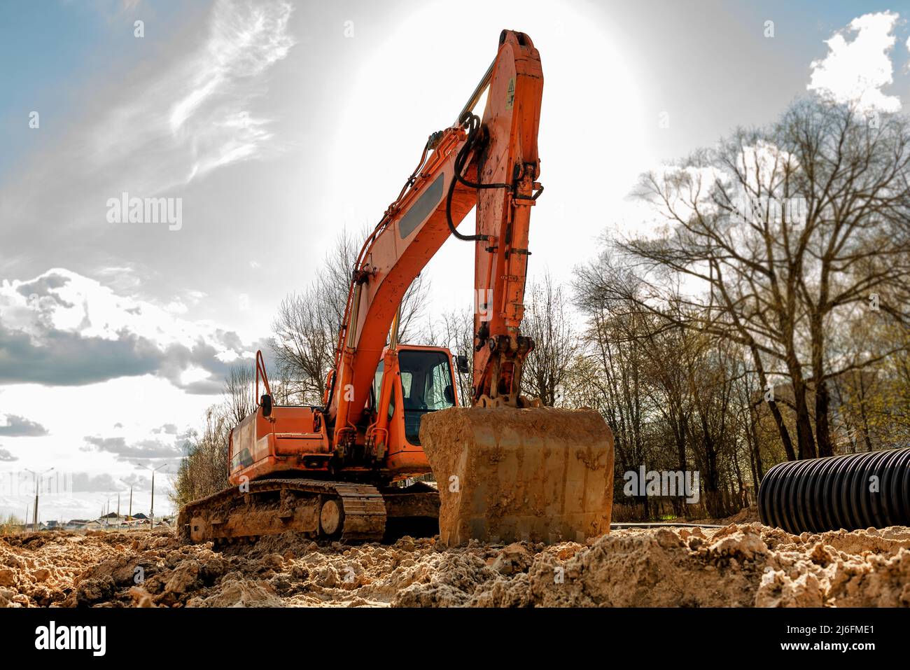 An excavator with a bucket digs a trench for laying pipes. Construction ...