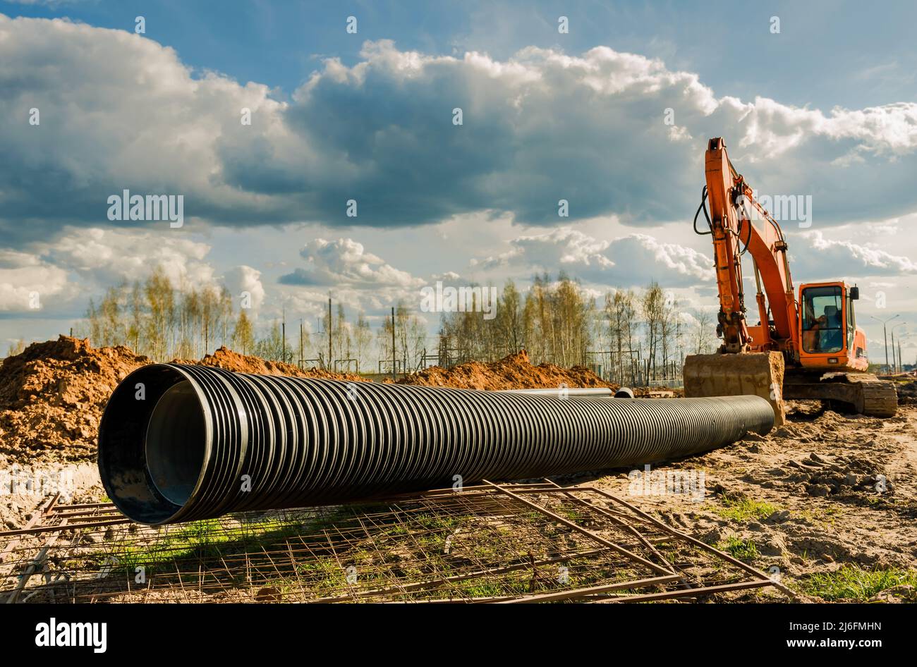 An excavator with a bucket digs a trench for laying pipes. Construction ...