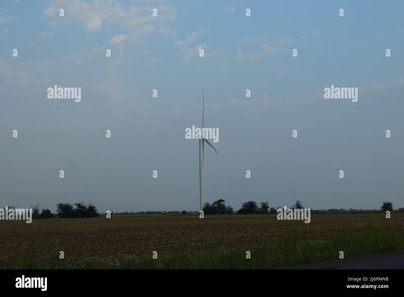 A field of windmills spin in front of a colorful evening sky. A wind ...