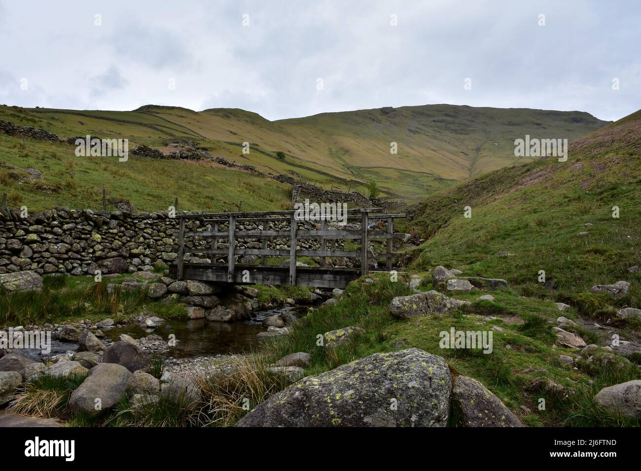 Wooden foot bridge through the fells of the lake district in England ...